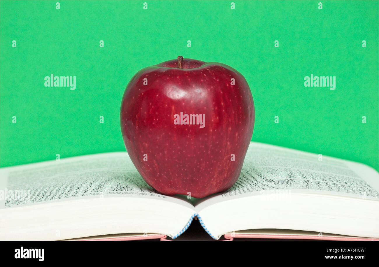 Red apple on top of open textbook Stock Photo - Alamy