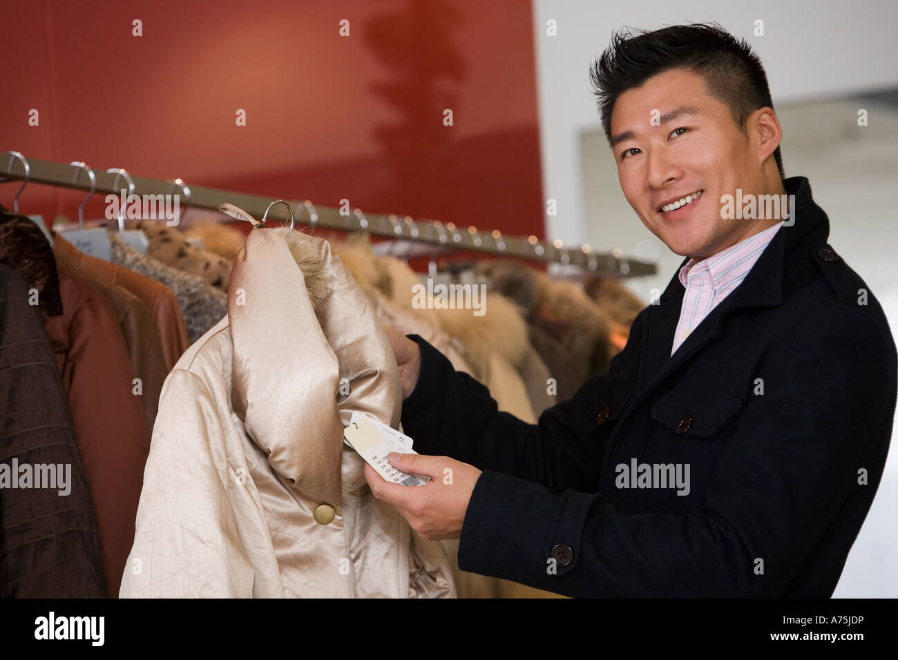 Man checking price tag on jacket Stock Photo - Alamy