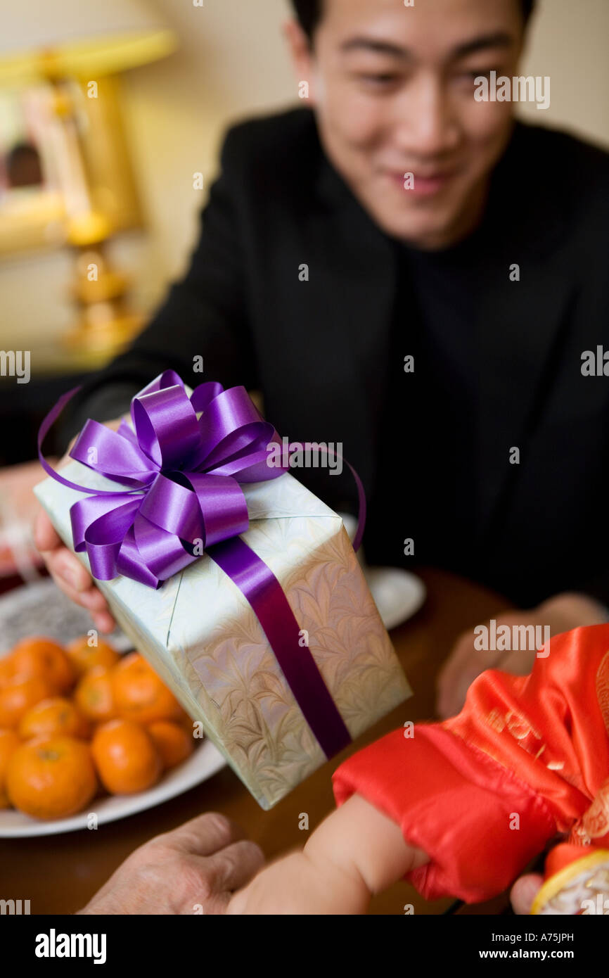 Man offering present across dinner table Stock Photo - Alamy