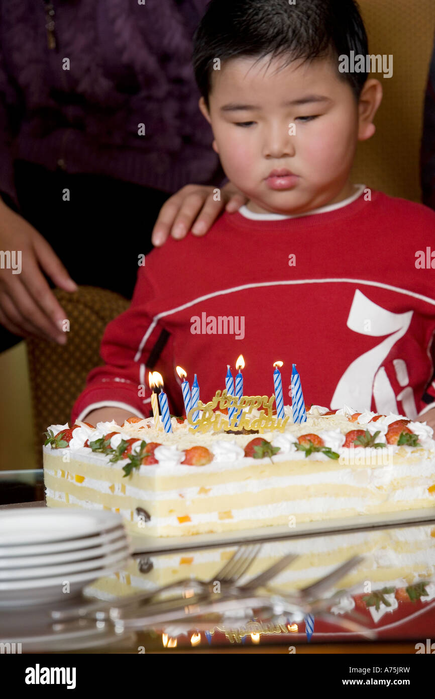 Young boy blowing out candles on birthday cake Stock Photo - Alamy