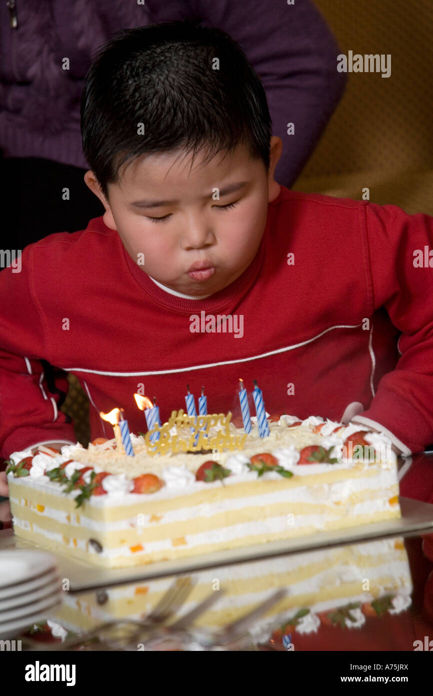 Young boy blowing out candles on birthday cake Stock Photo - Alamy