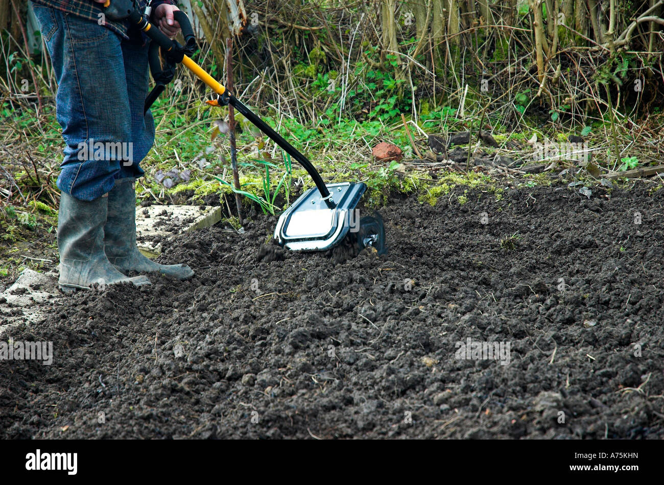 A gardener tills his plot, using a petrol rotavator Stock Photo - Alamy