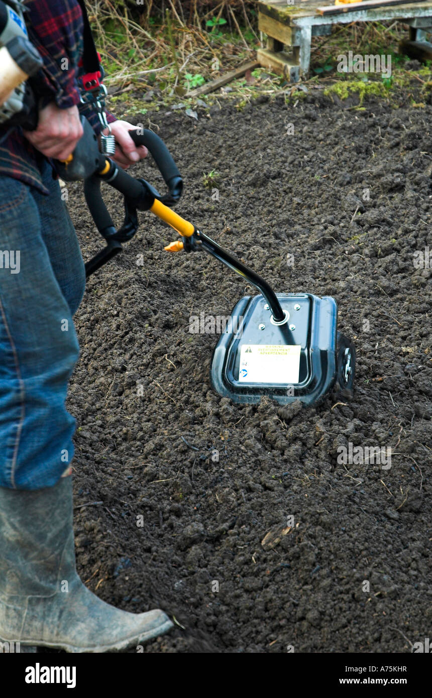A gardener tills his plot, using a petrol rotavator Stock Photo - Alamy