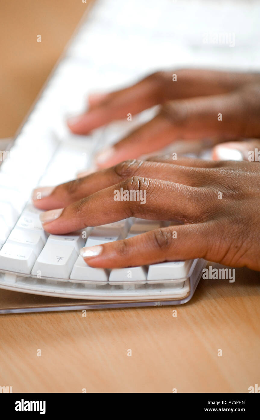 Close up picture of a black womans hands typing on a white keyboard ...