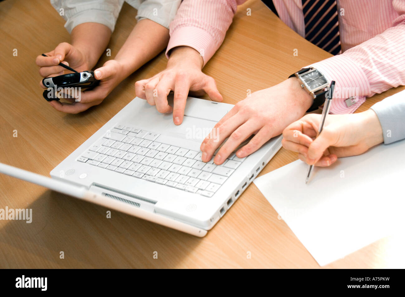 Close up of office workers hands with a laptop computer pda and note ...