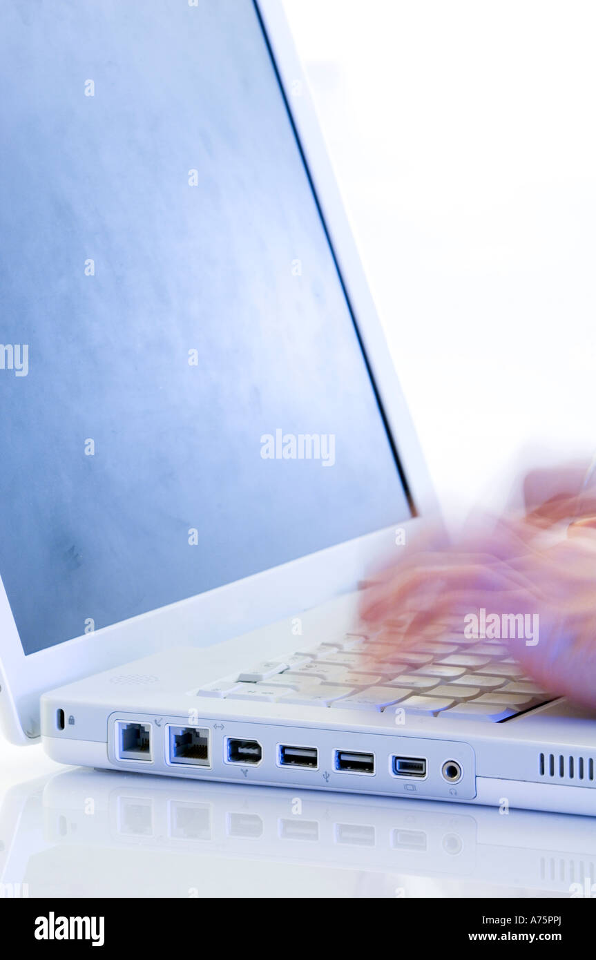 Hands typing at speed on laptop computer keyboard against white ...