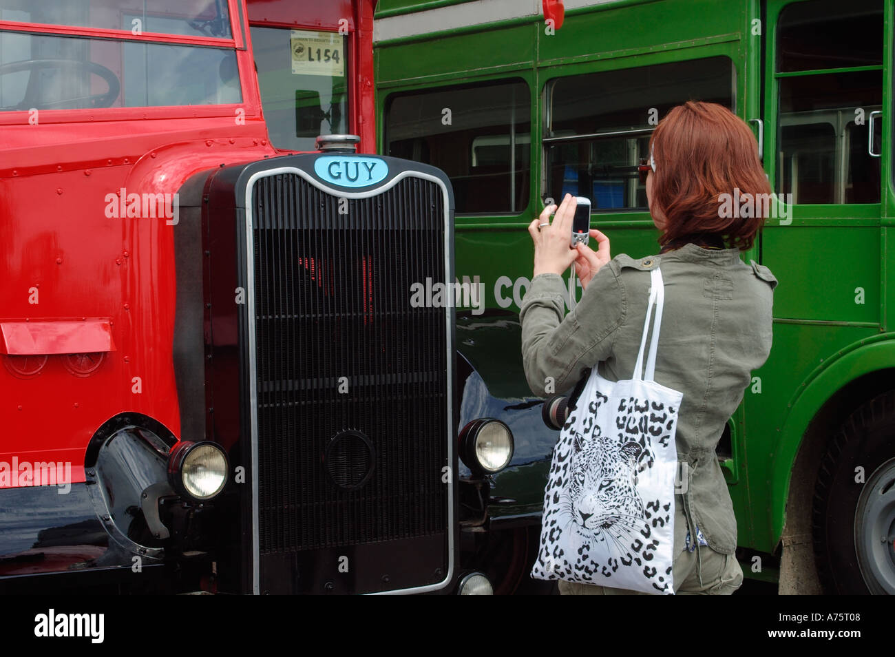 Woman takes a picture on mobile of an Old London double decker bus at ...
