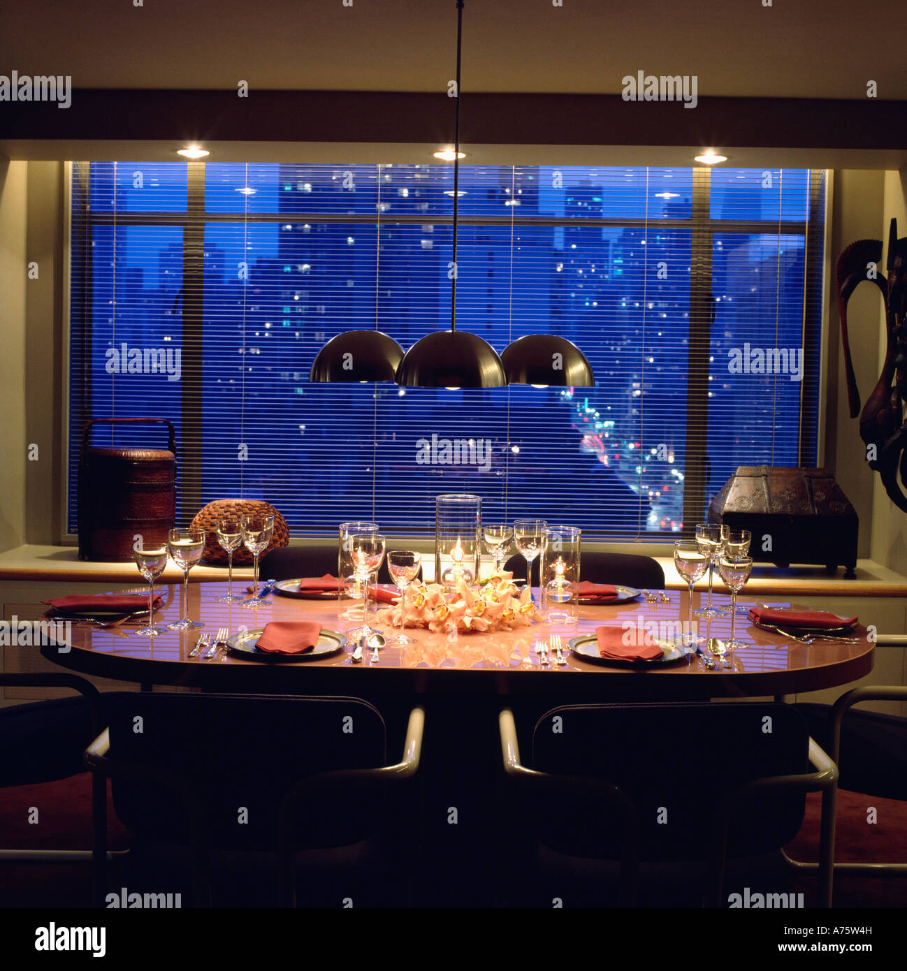 Pendant light above diningtable with view of the city through large ...
