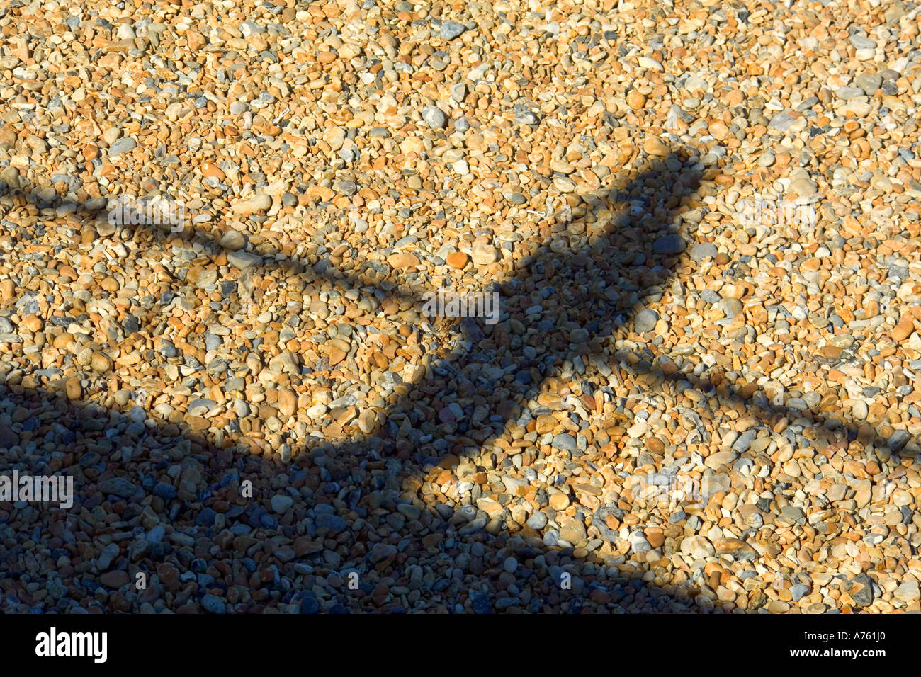 Shadow of a person eating an ice cream on a pebbley beach Stock Photo ...