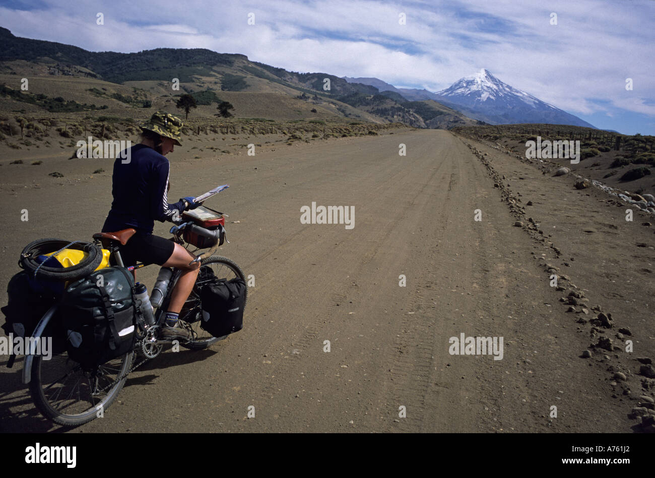 Lone female touring cyclist on rough road in Argentina reading a map ...