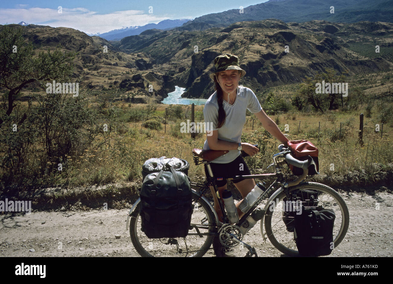 Female expedition touring cyclist posing next to river and mountains on ...