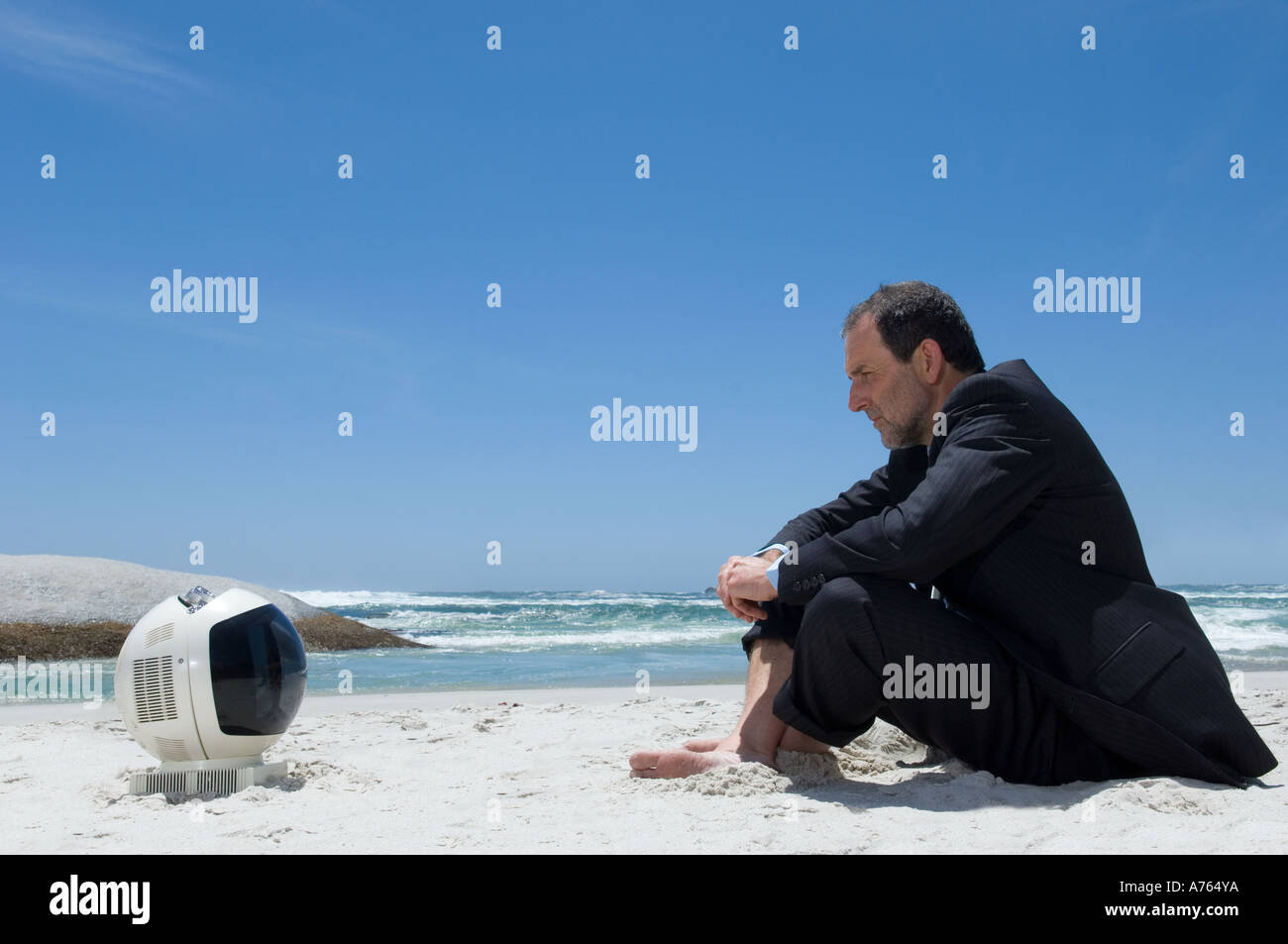 Business man looking at tv on beach Stock Photo - Alamy