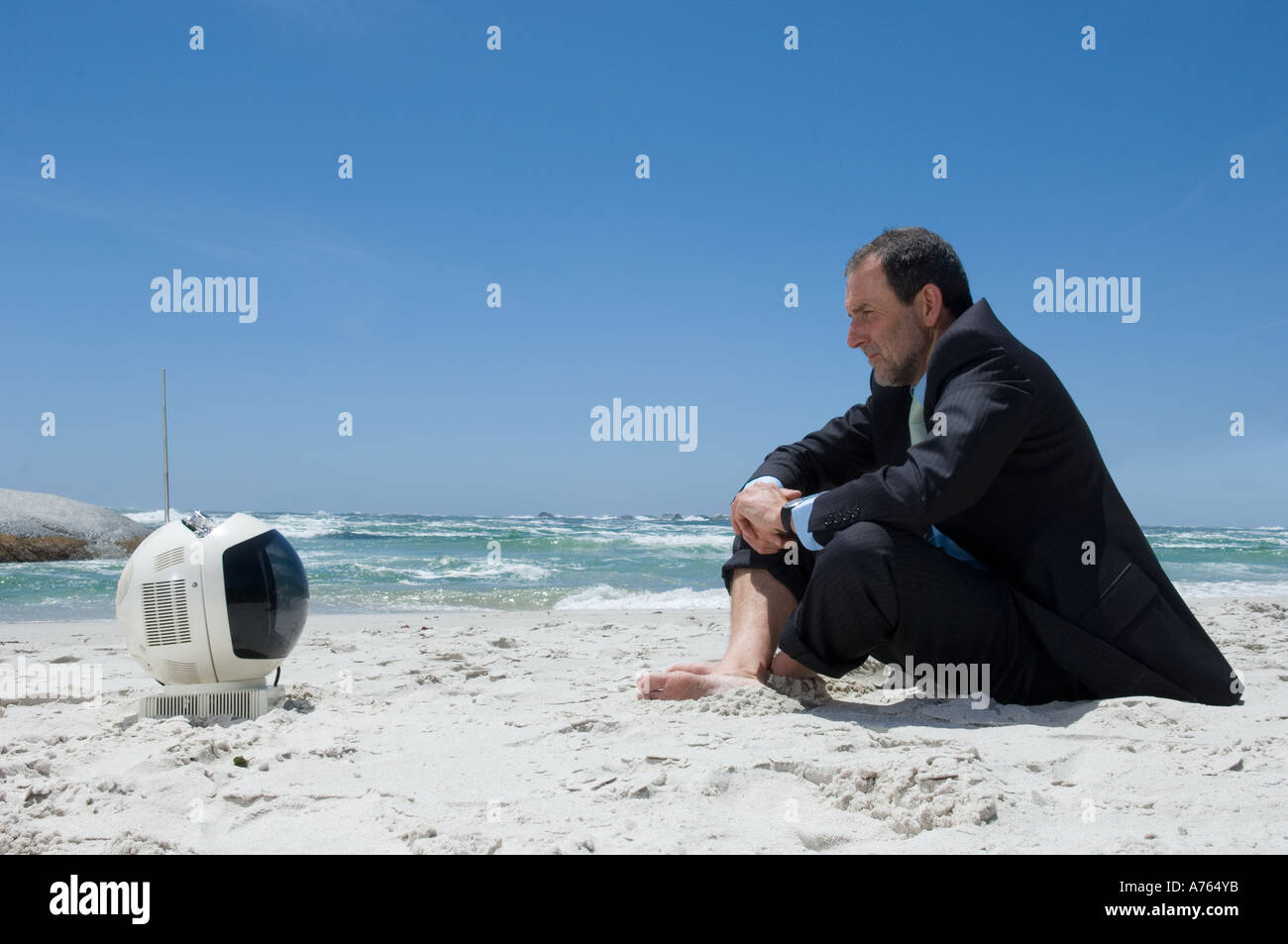 Business man looking at tv on beach Stock Photo - Alamy