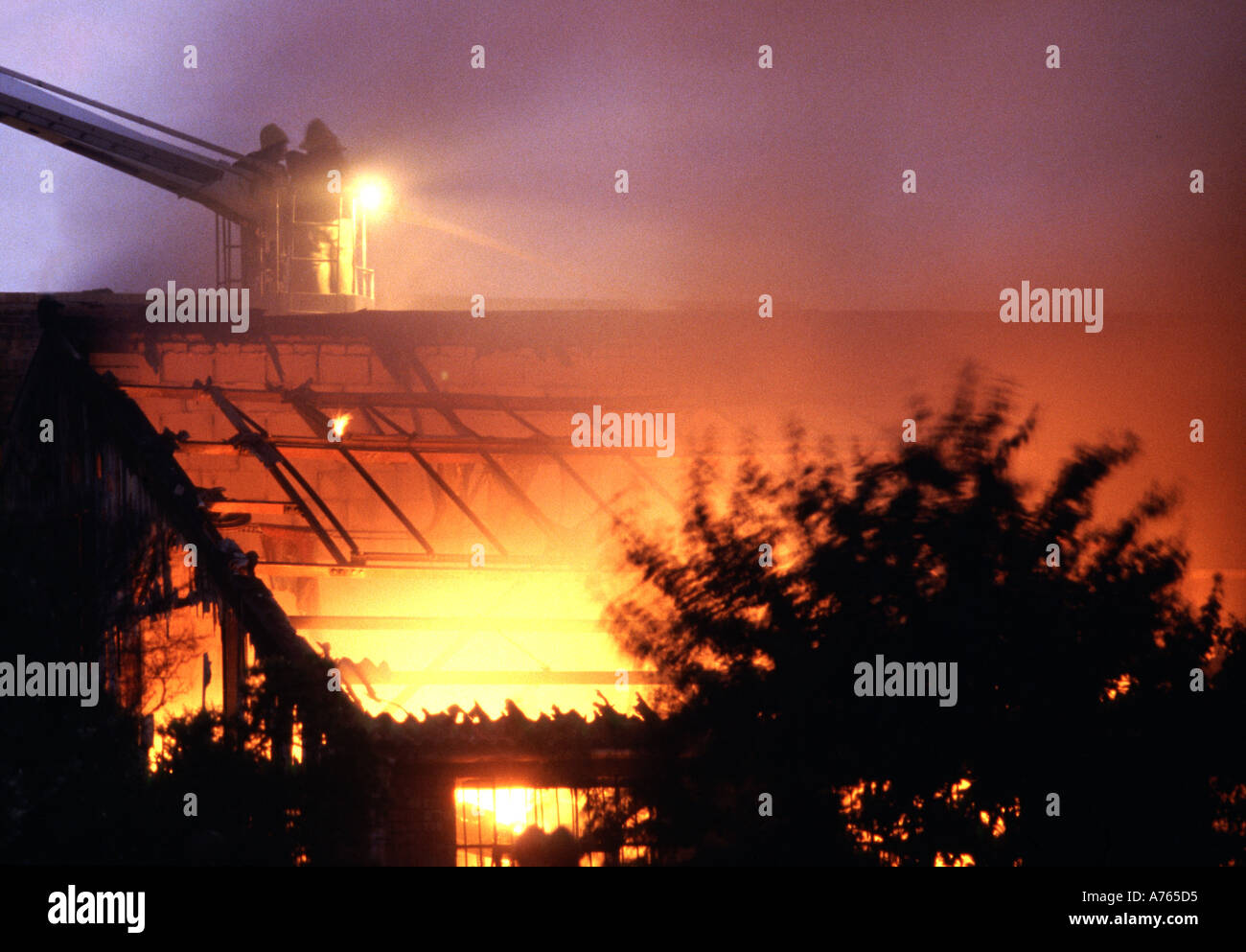 Industrial warehouse unit on fire with fireman crew on hydraulic ...