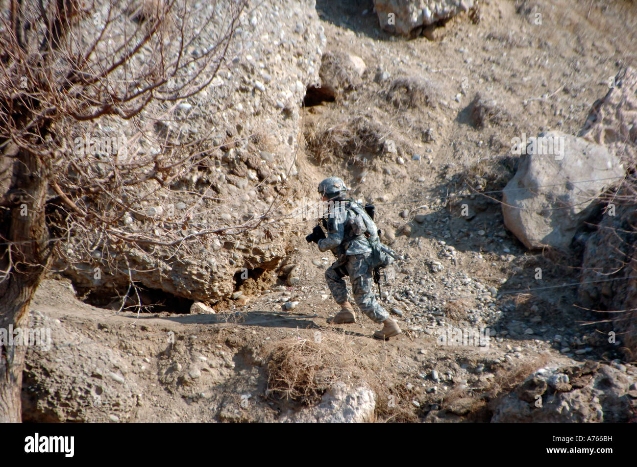 U.S. Army soldier walks up the side of a hill to look at caves near the ...