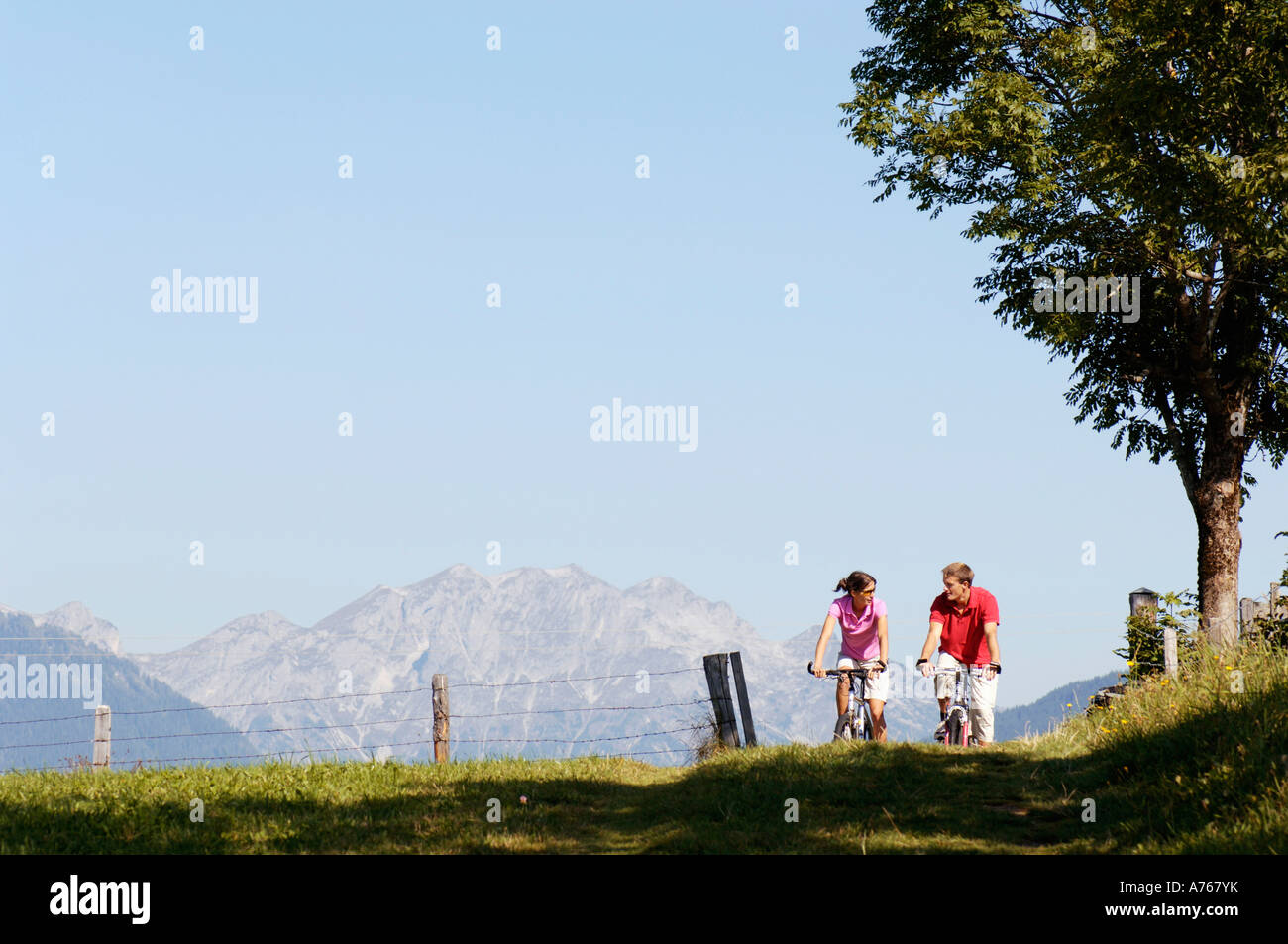 Young couple riding mountain bike, face to face Stock Photo - Alamy