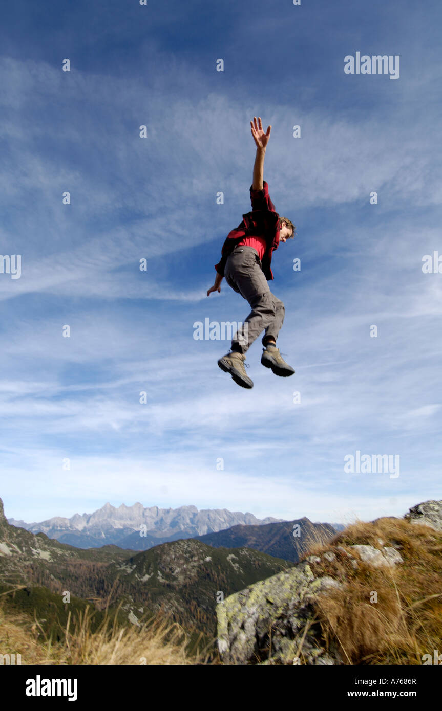 Man jumping over mountains, arms out, side view Stock Photo - Alamy
