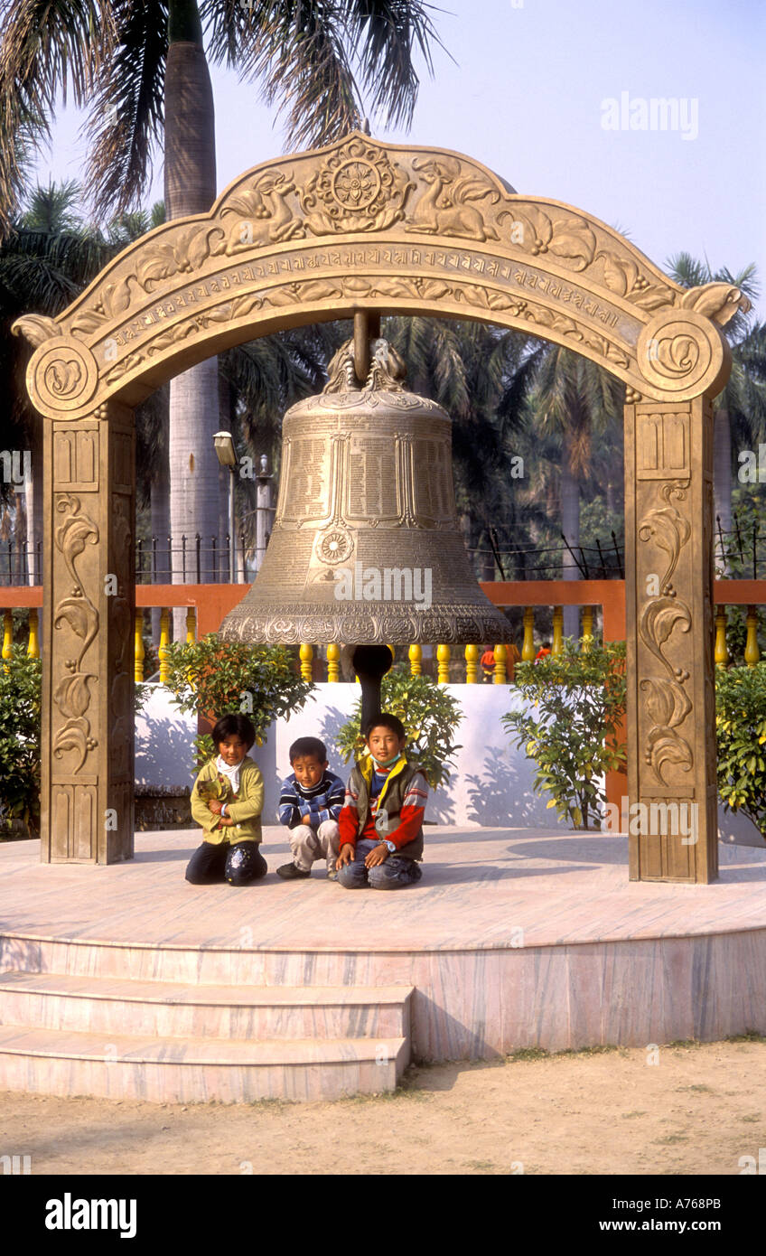 Three Tibetan boys pose under huge brass bell with ornate frame at ...