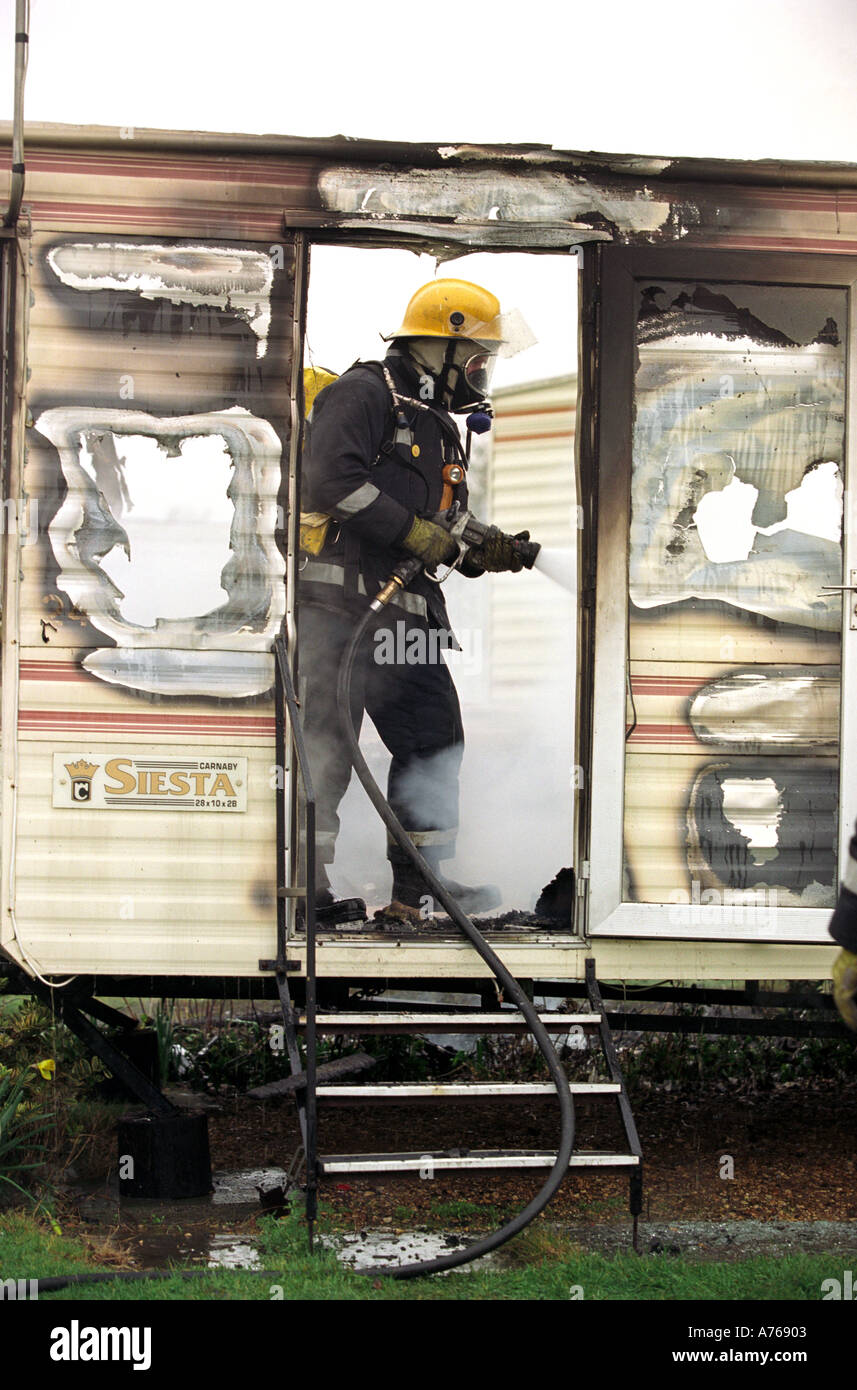 A Firefighter in action at a caravan fire, Britain UK Stock Photo - Alamy
