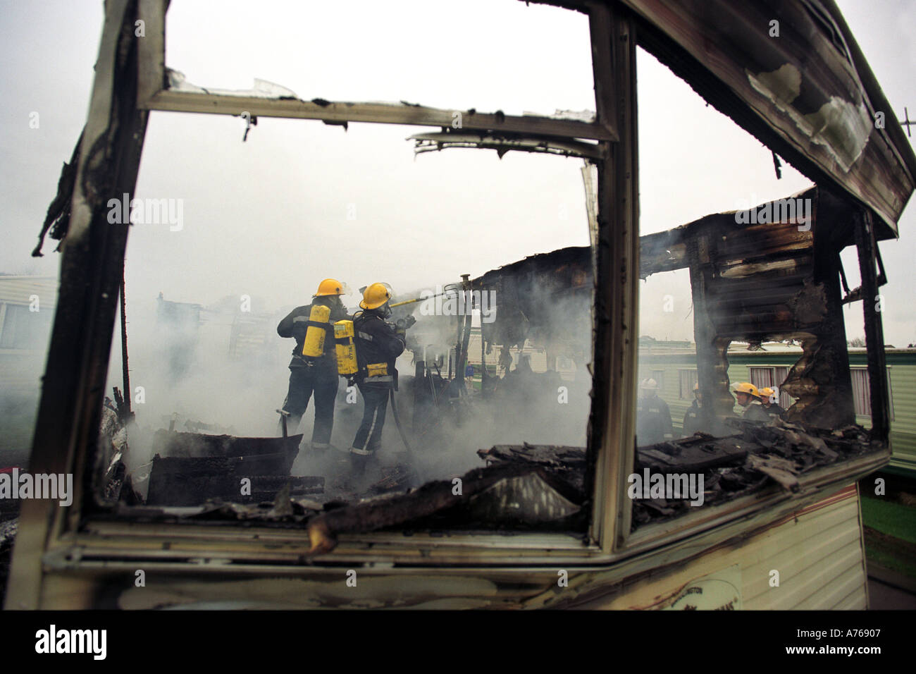 A Firefighter in action at a caravan fire, Britain UK Stock Photo - Alamy