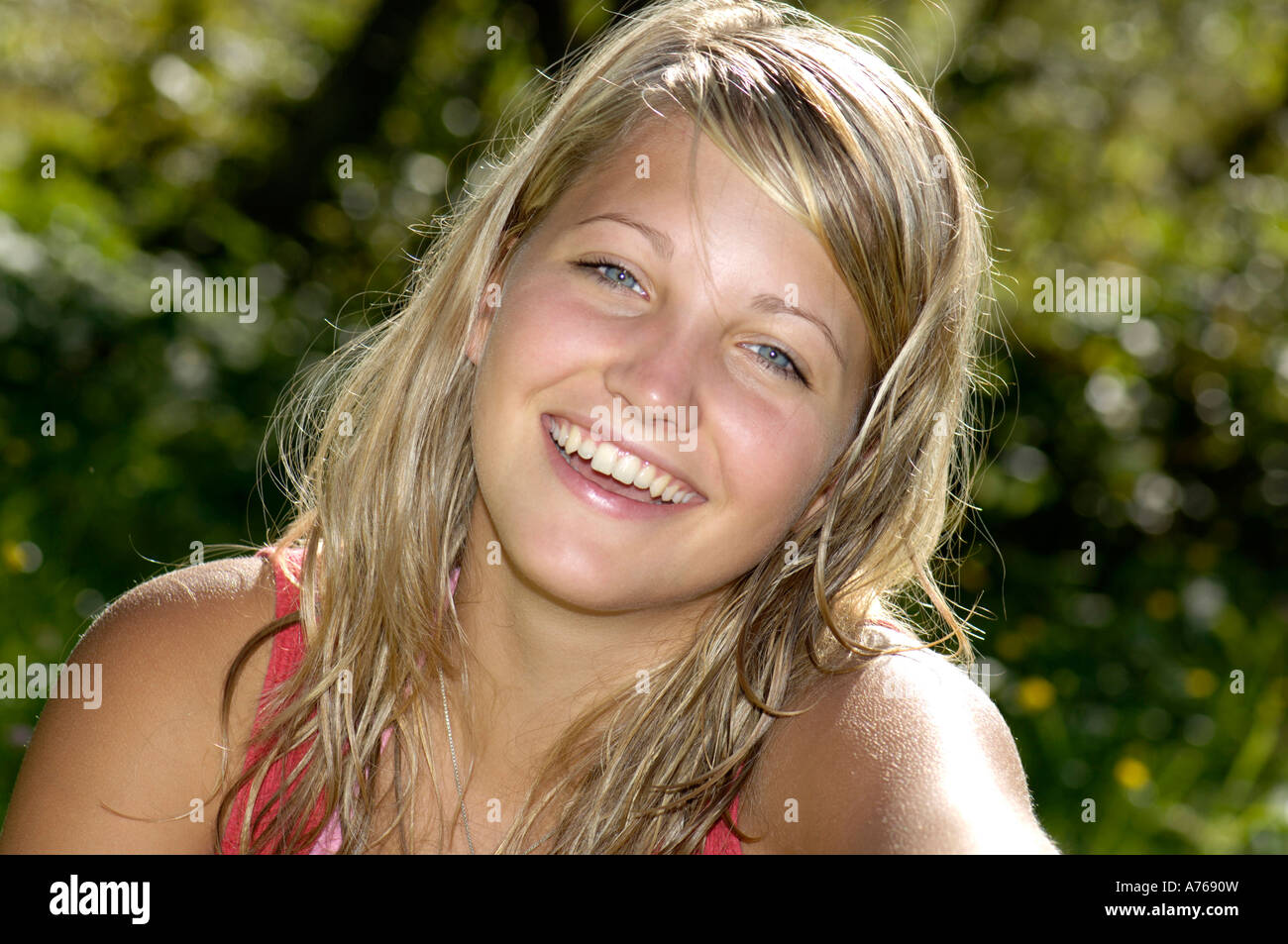 Teenage girl (16-17) sitting in meadow, smiling, close-up, portrait ...