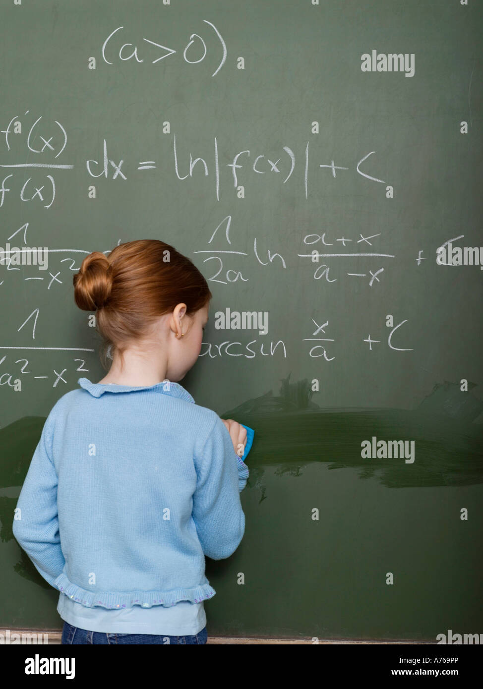 Girl standing in front of blackboard, solving arithmetic problem Stock ...