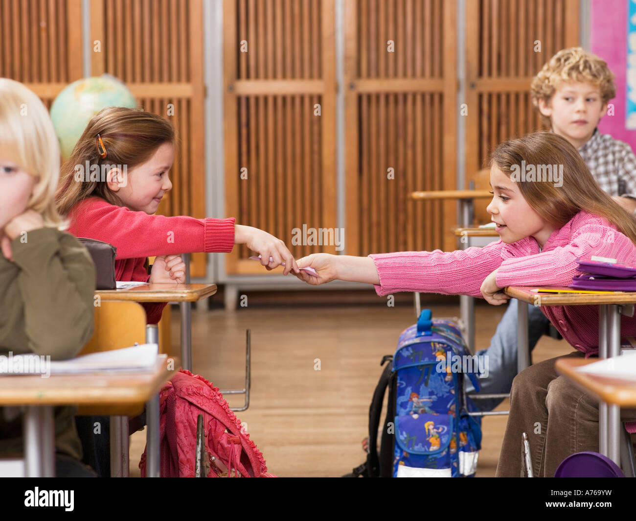 Girls (4-7) exchanging notes in classroom Stock Photo - Alamy