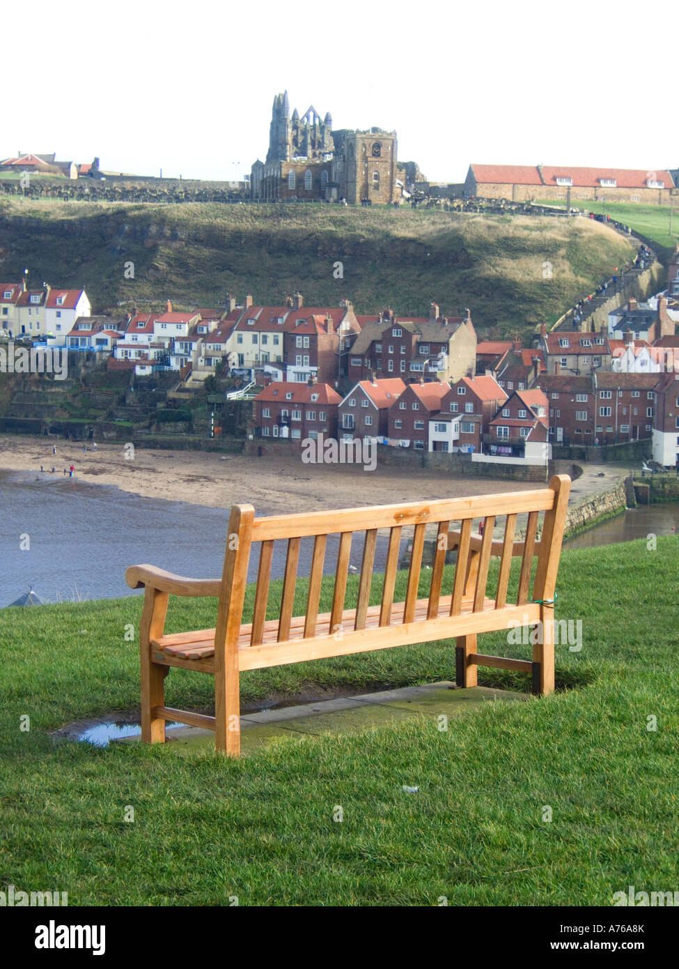 Empty wooden bench on West cliff top with view of Whitby Abbey on the ...