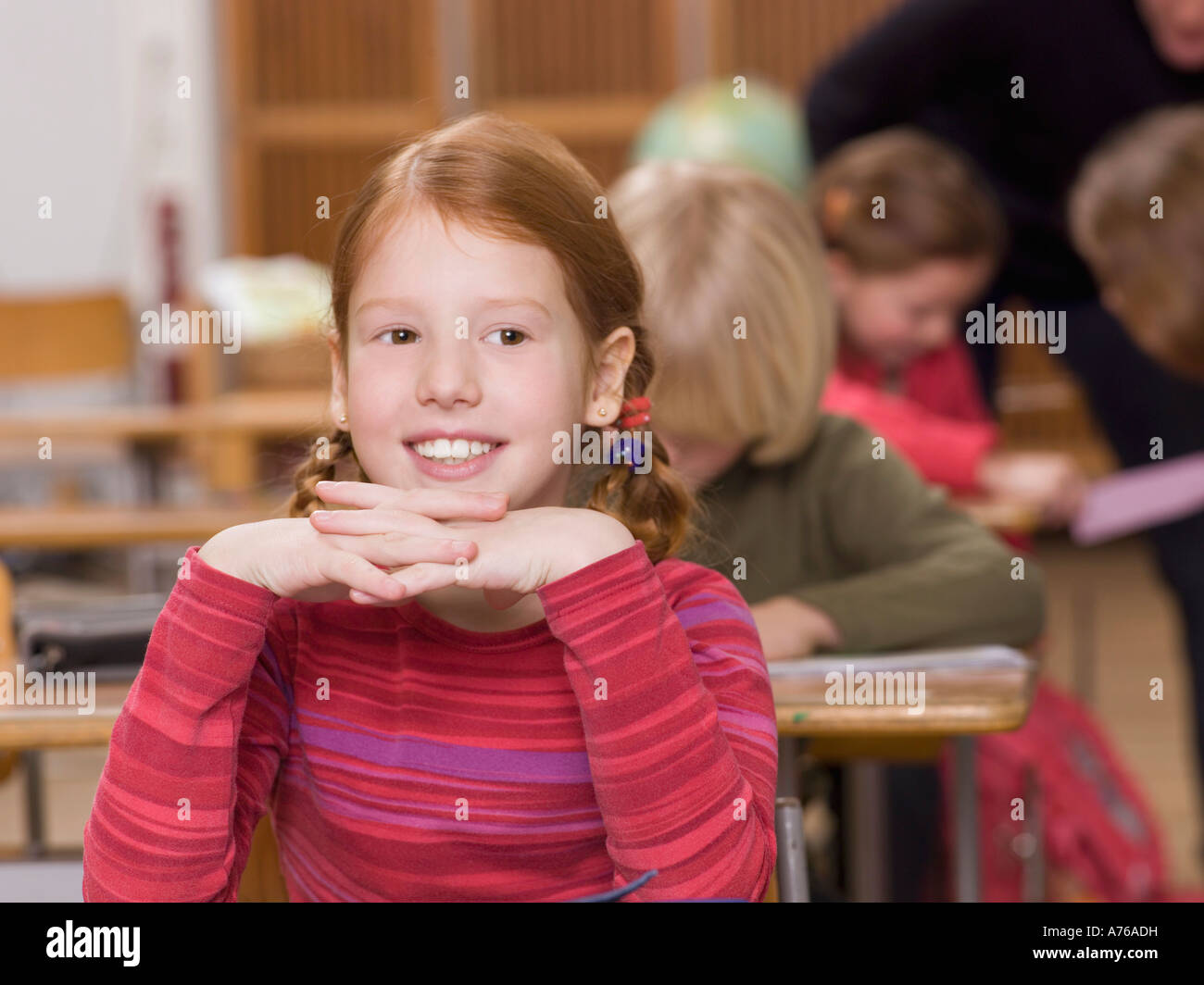 Girl (4-7) in classroom, smiling, head on hands, close-up Stock Photo ...