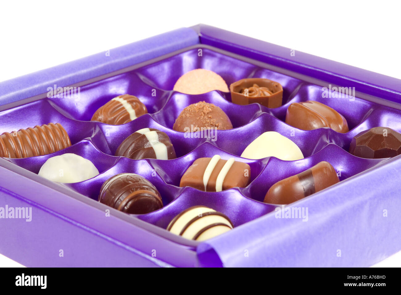 Assortment of chocolates in purple tray on a pure white background ...