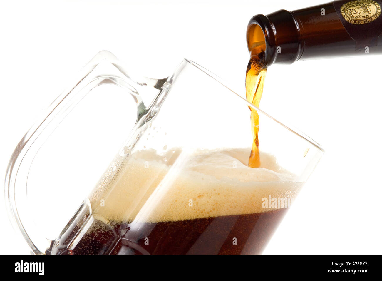 Pint of dark beer being poured into glass on a pure white background ...