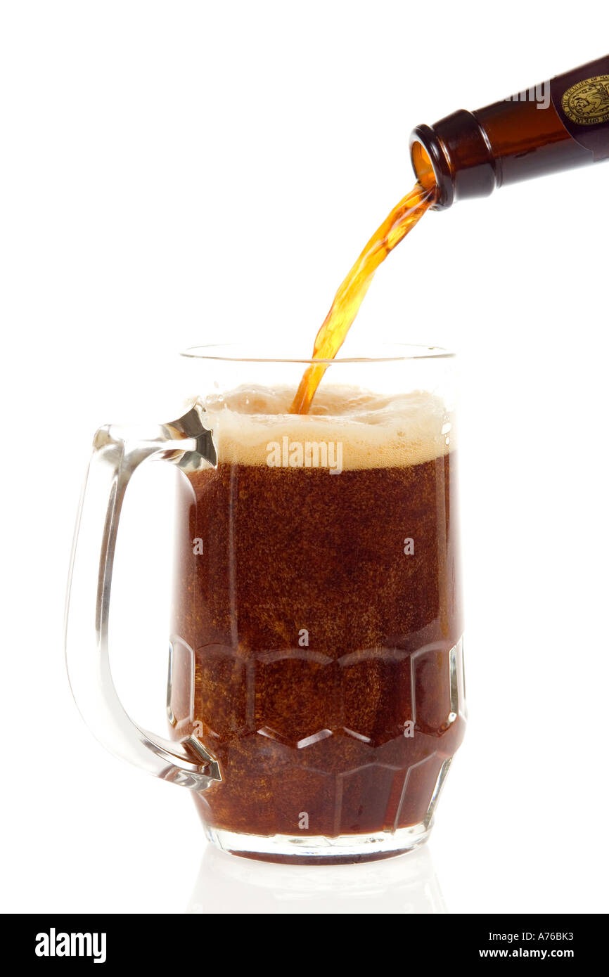 Pint of dark beer being poured into glass on a pure white background ...