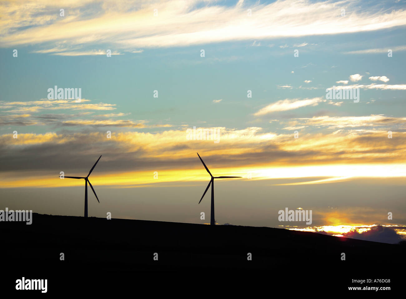 Two wind turbines on a wind farm on the Cornish countryside at sunset ...