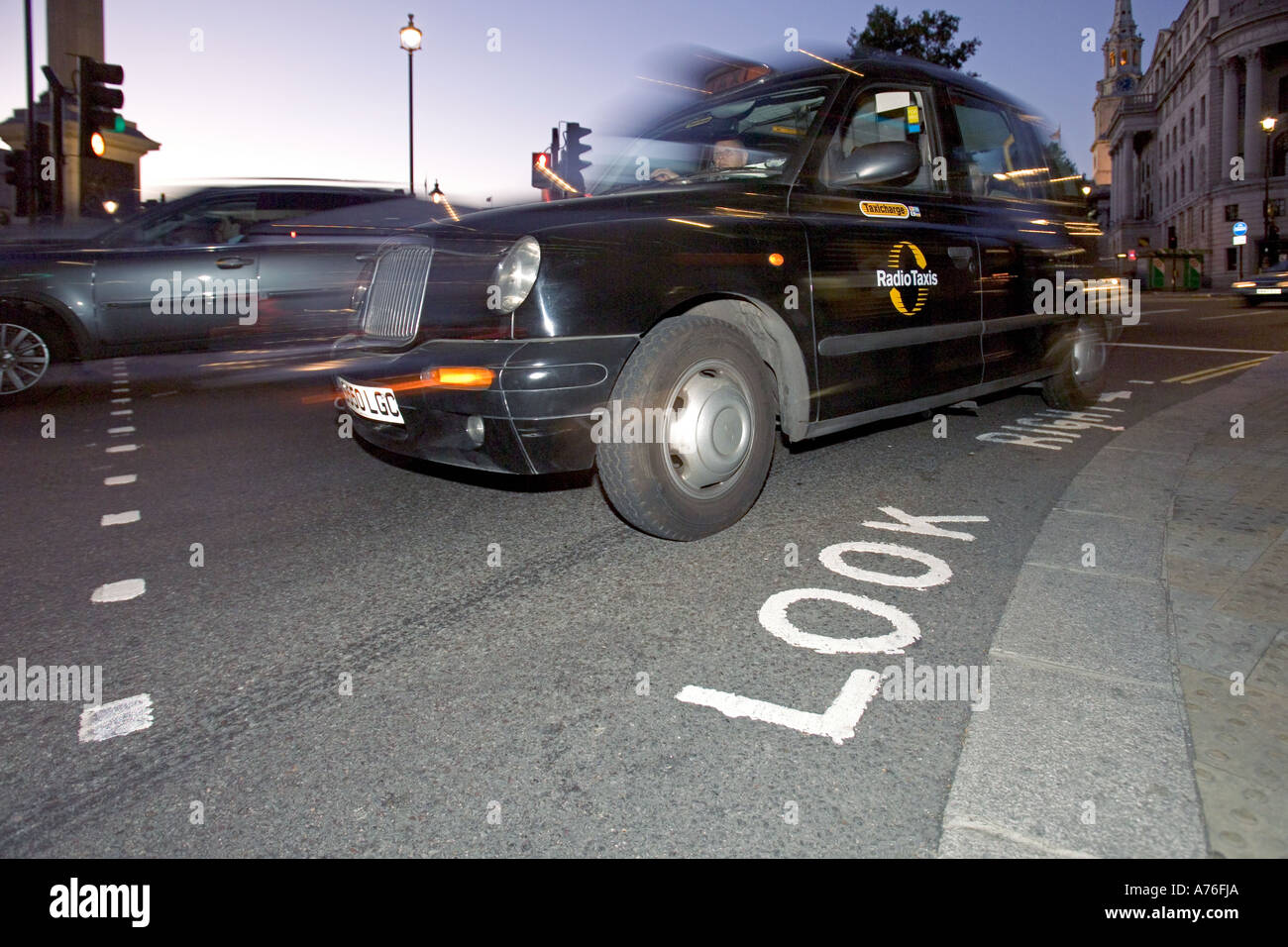 Low wide angle and flash fill of a traditional black taxi driving round ...