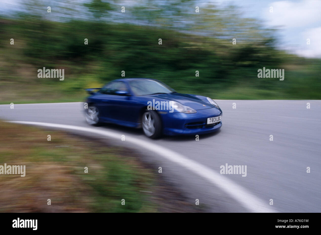 Porsche 911 Carrera being driven at speed around a corner on a country ...
