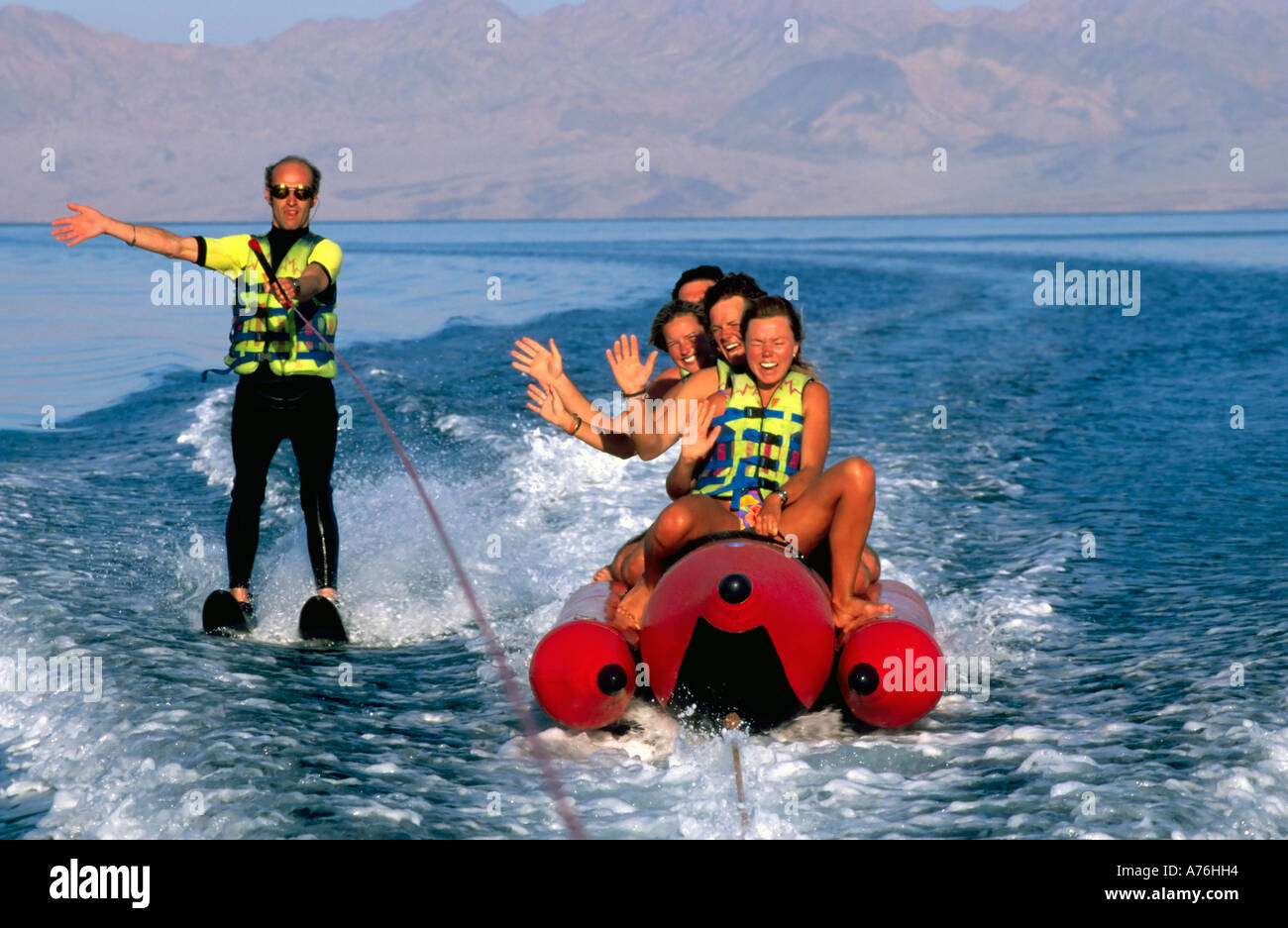 Water skier and banana boat riders (tourists) waving and having fun on ...