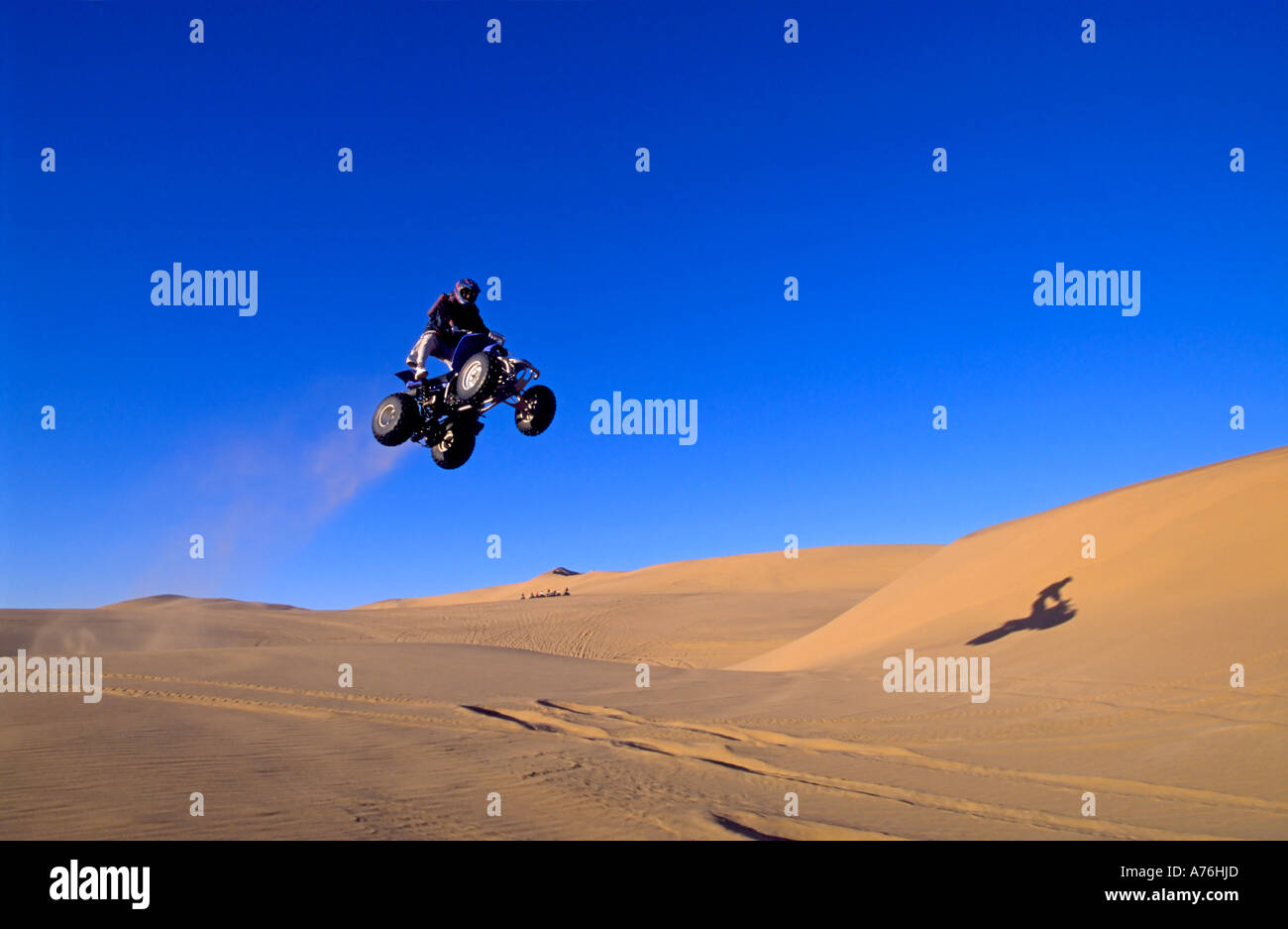 A Quad biker performing freestyle jumps on the sand dunes of the ...