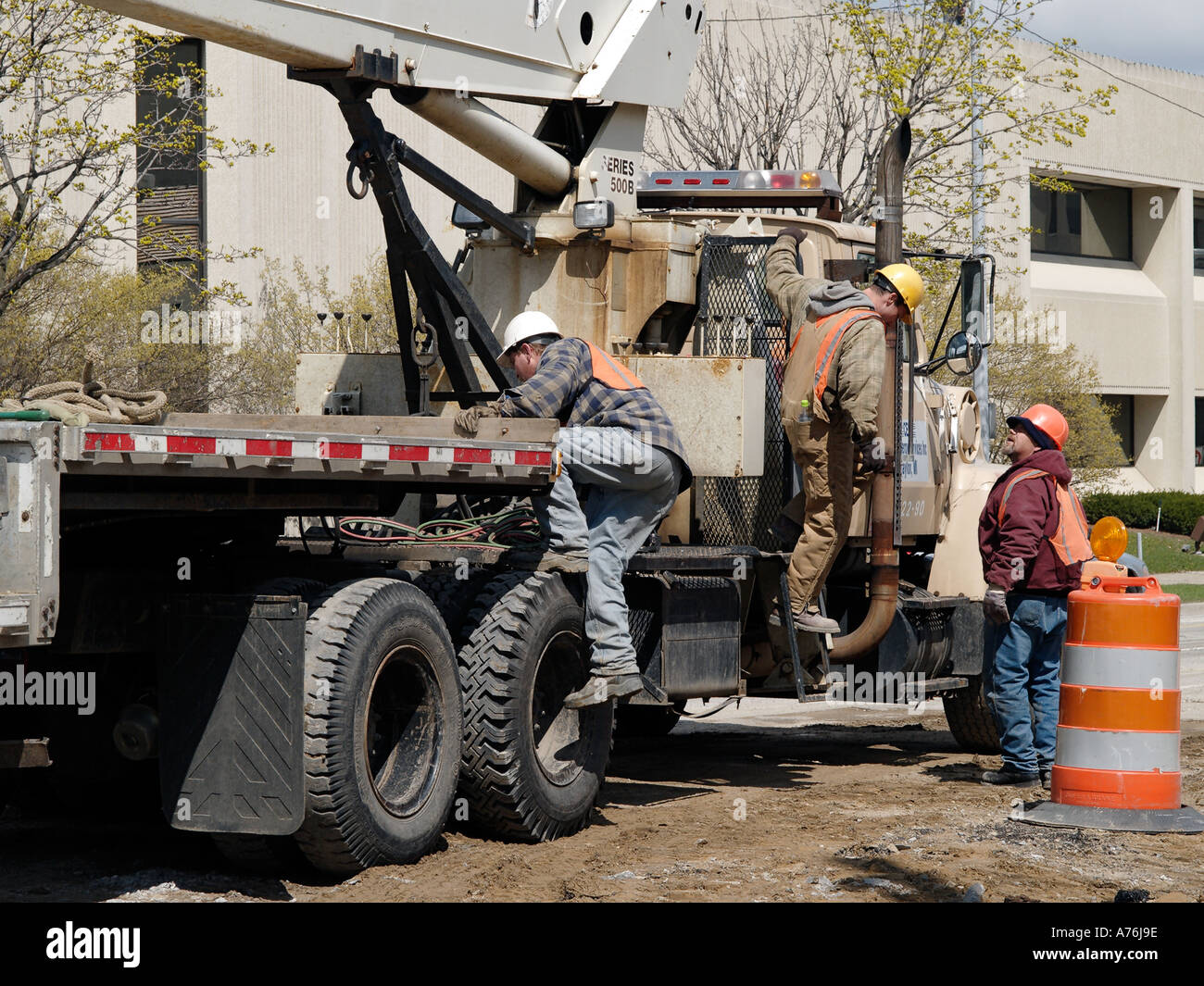 Construction workers manning a flatbed truck with a crane Stock Photo ...