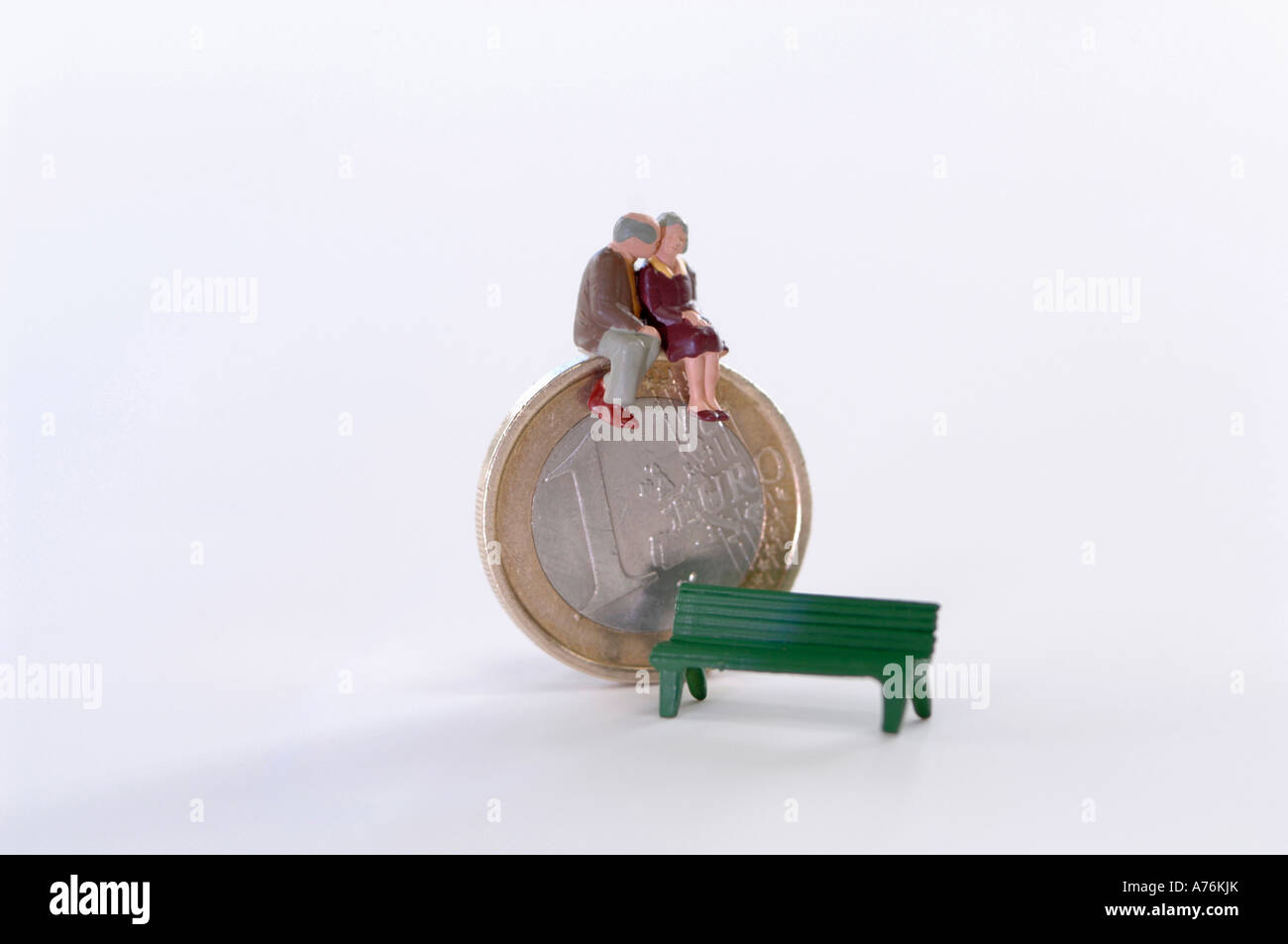 Figurines sitting on coin, bench aside Stock Photo - Alamy