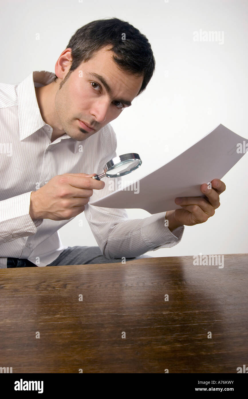 Young man holding magnifying glass with paper, portrait Stock Photo - Alamy