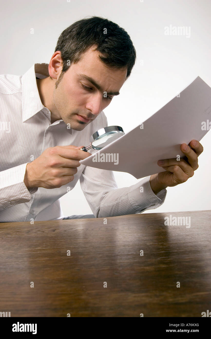 Man reading document with magnifying glass Stock Photo - Alamy
