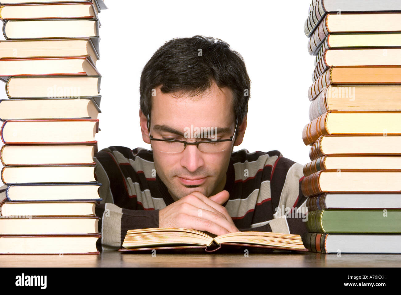 Young man reading by piled books Stock Photo - Alamy
