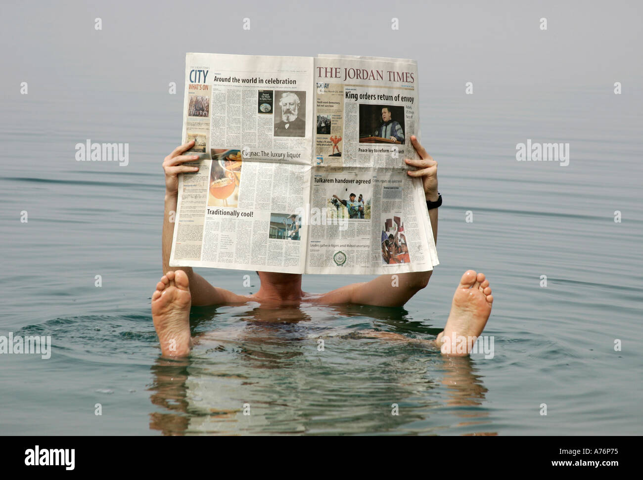 Tourist floating in Dead Sea reading newspaper Stock Photo - Alamy