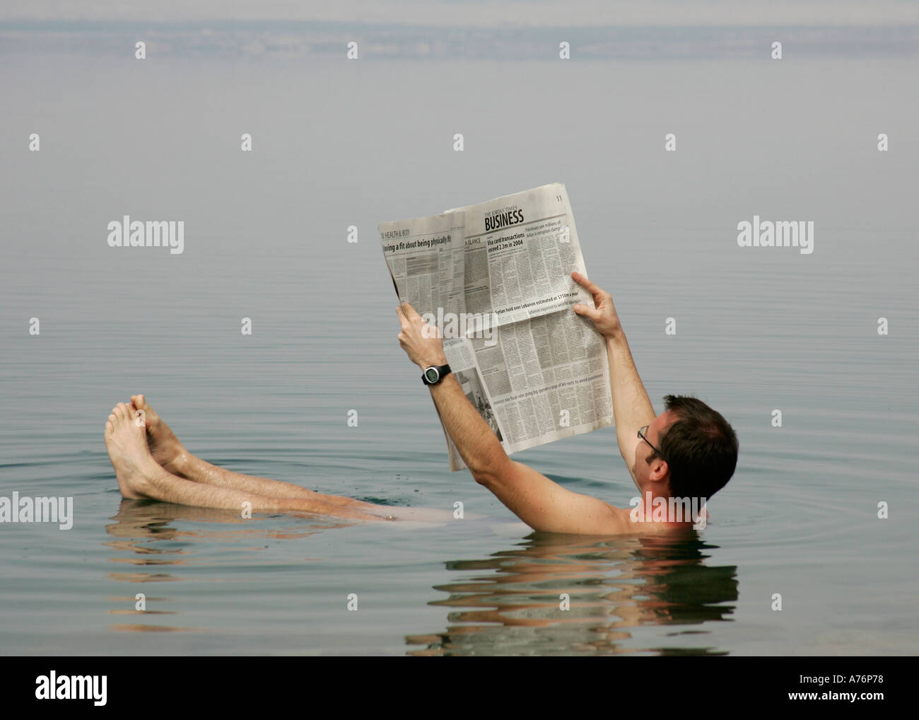 Tourist floating in Dead Sea reading newspaper Stock Photo - Alamy