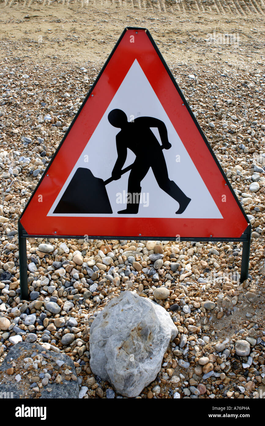 Men at work warning sign on pebble beach with granite rock Stock Photo ...