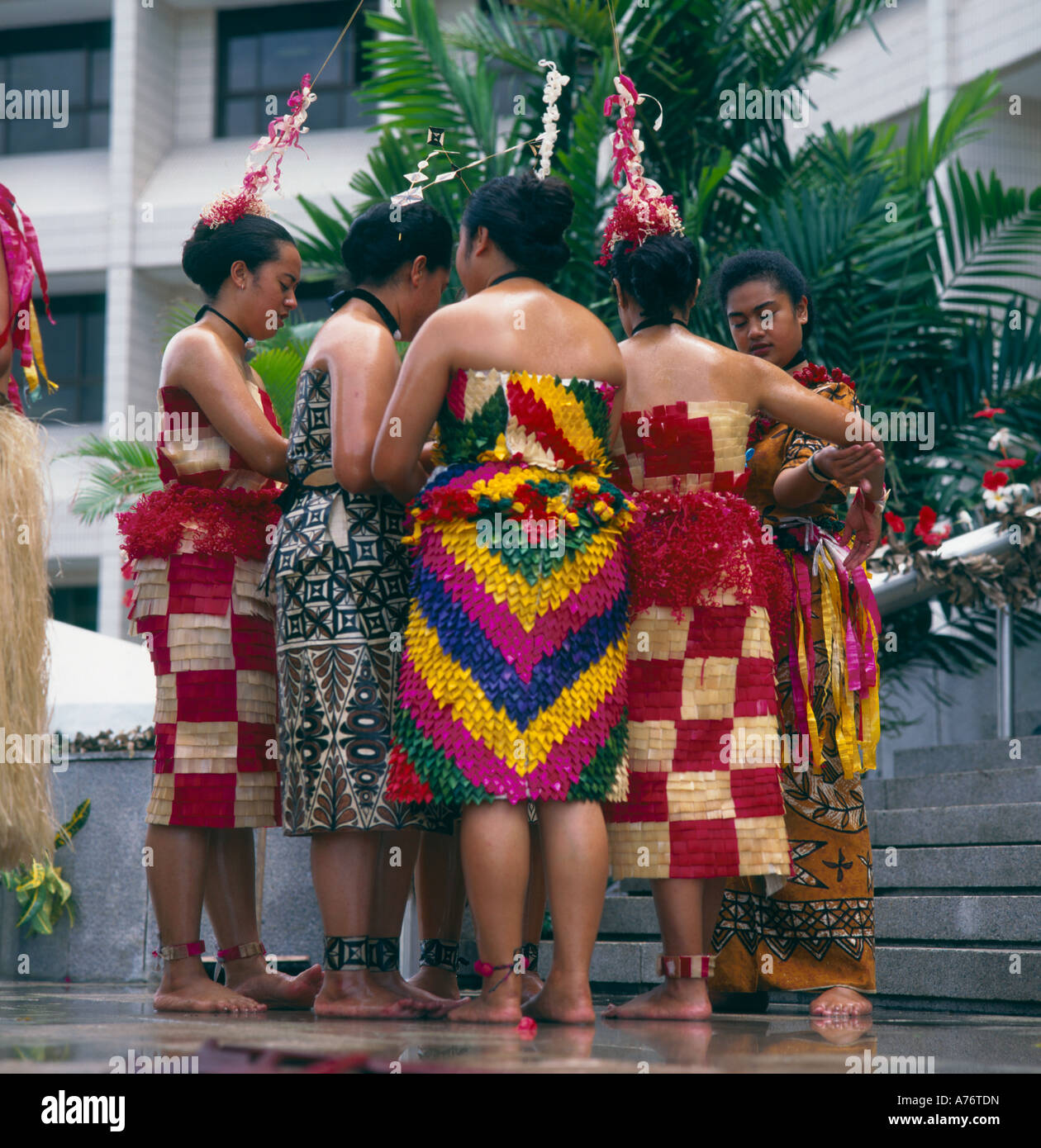 Group of Tonga female dancers apply oil to their skin as a traditional ...