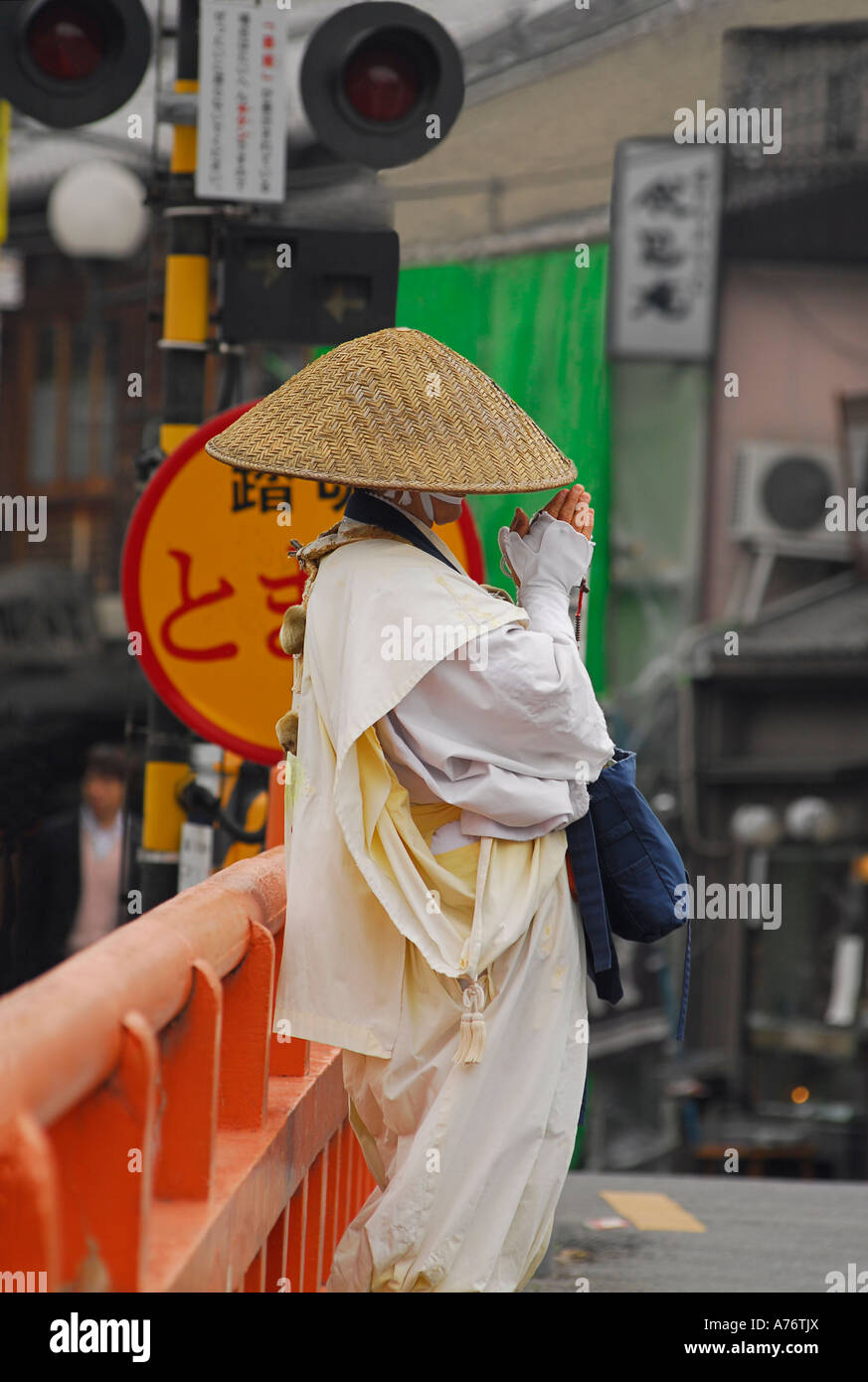 Japanese wandering monk offering prayer on a bridge in Inari Kyoto ...