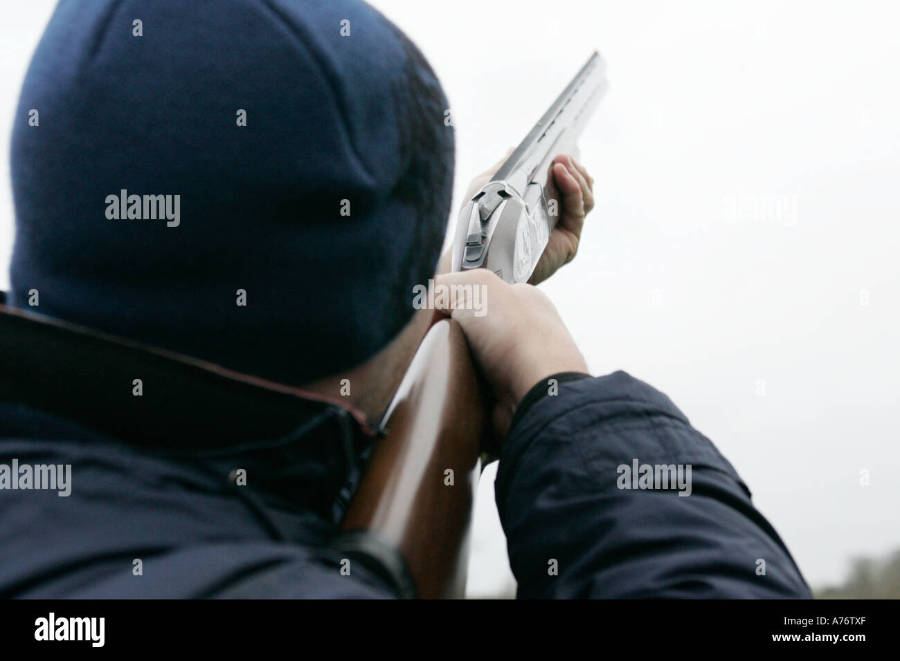 Man in woolen hat aiming shotgun into the sky on december shooting day ...