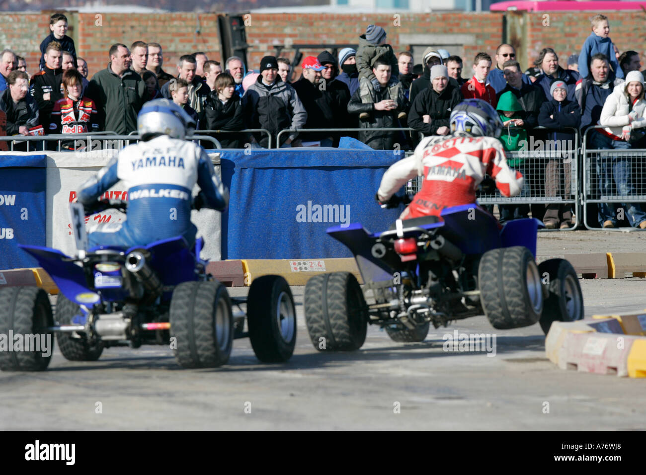 quad racers lean into the corner in front of spectators at the ...