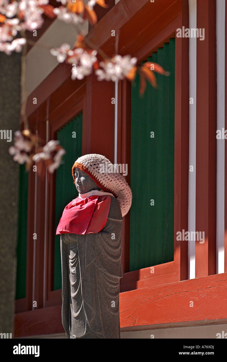 Jizo carving with bib and hat framed by cherry blossom KoyaSan Wakayama ...